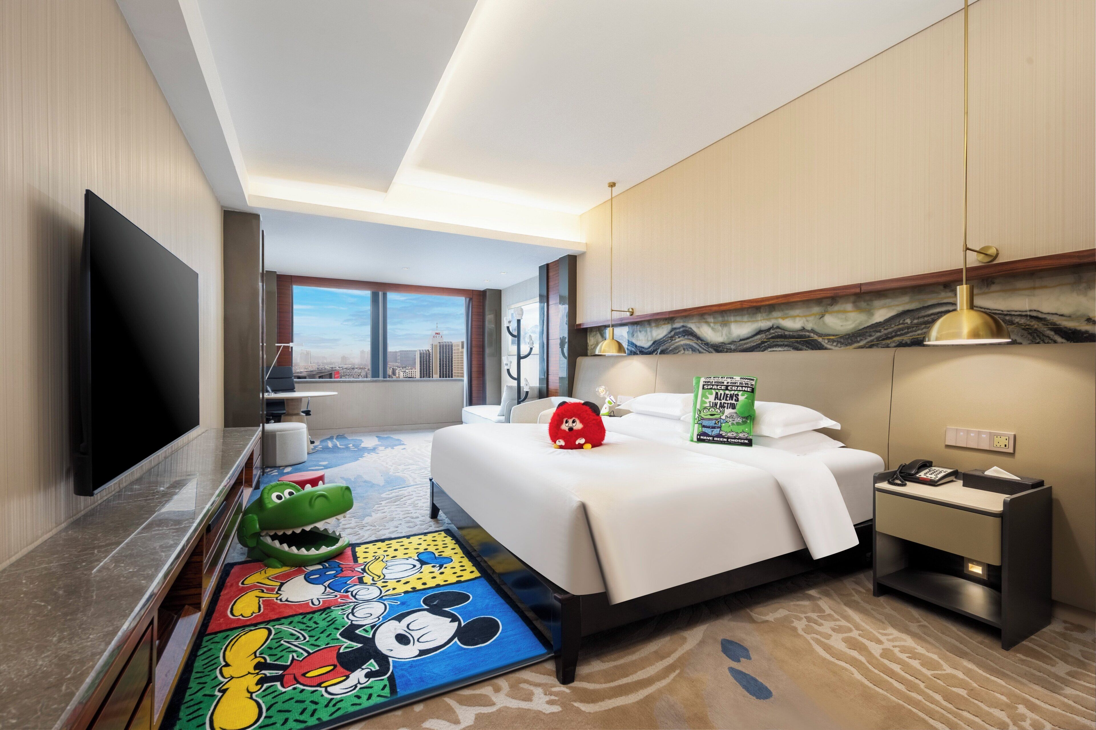 Quarto de hotel com uma cama grande, televisão de tela plana, mesa de cabeceira e vista para a cidade pela janela.