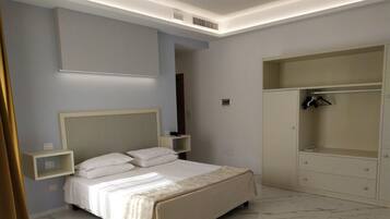 Quarto com cama, mesas de cabeceira, guarda-roupa e espelho.