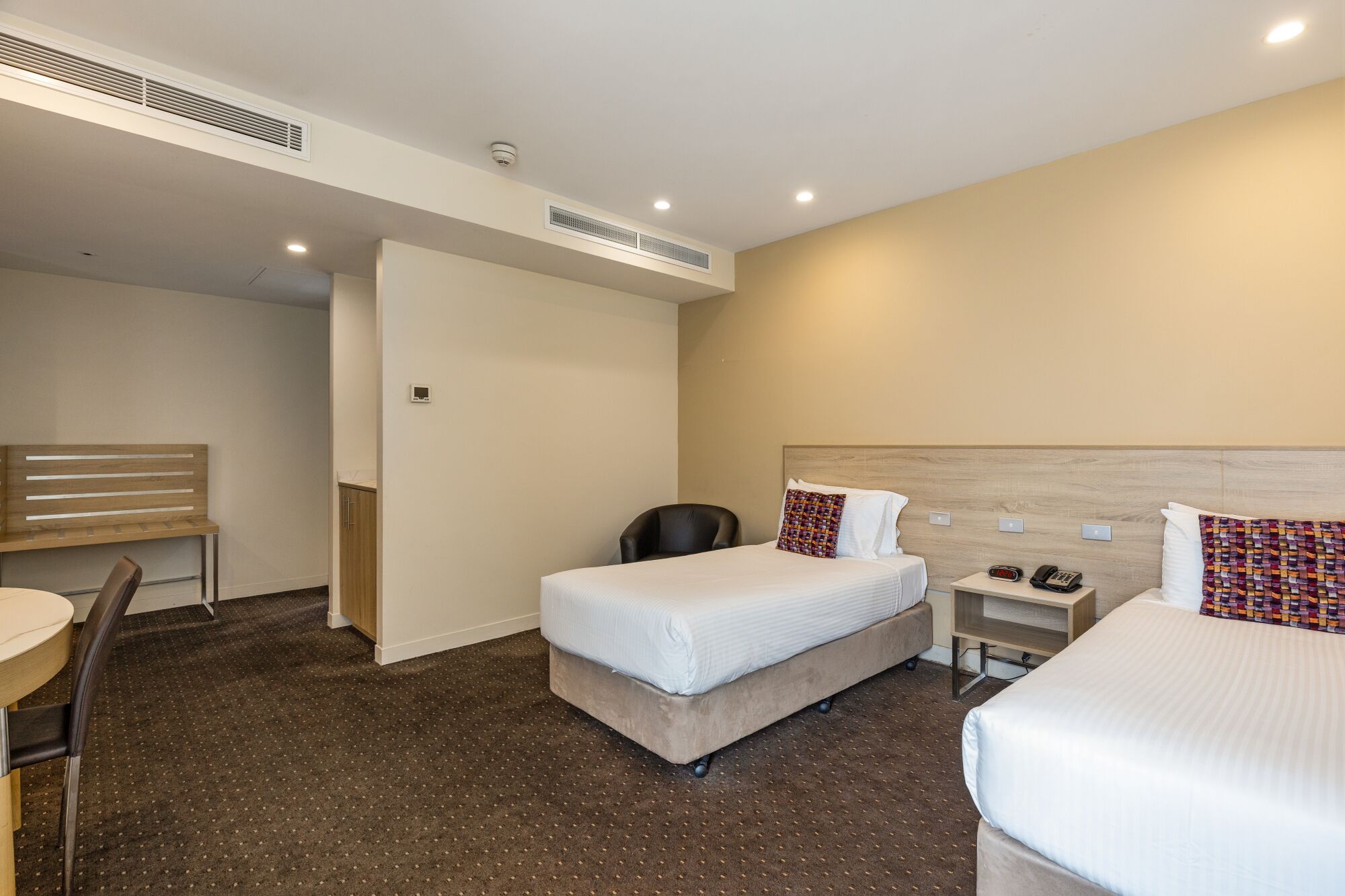 Quarto de hotel com duas camas, uma escrivaninha e uma cadeira.