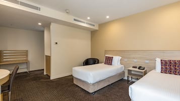 Quarto de hotel com duas camas, uma escrivaninha e uma cadeira.