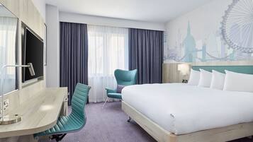 Quarto de hotel com uma cama grande, uma escrivaninha com cadeira, televisão e um mural com vista urbana.