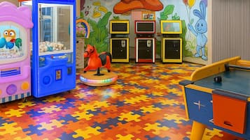 Uma sala de jogos infantil com piso de quebra-cabeça colorido, estruturas de recreação e um mural.