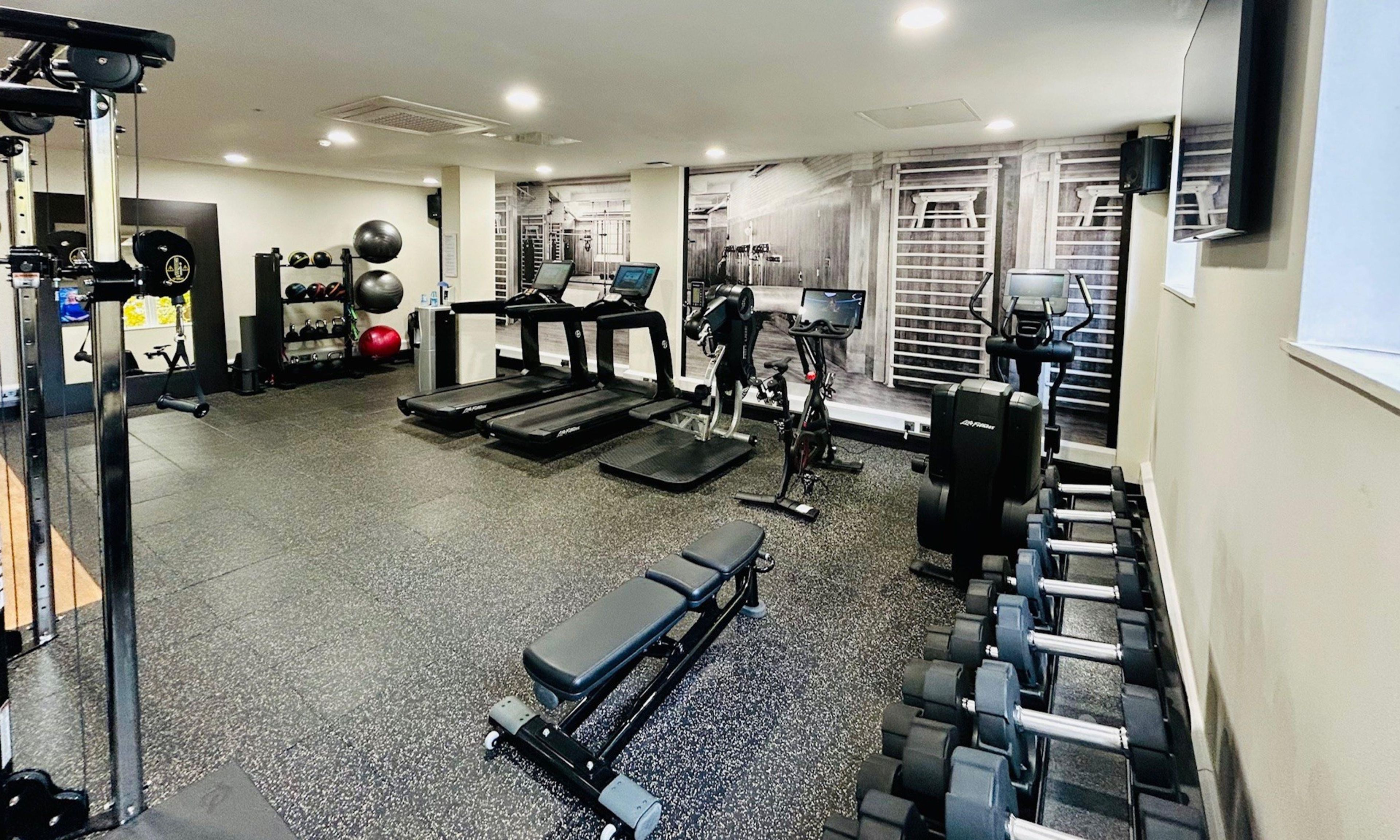 Uma academia com esteiras, bicicleta ergométrica e aparelhos de musculação.