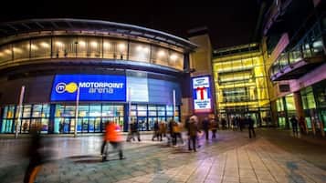 Um edifício moderno com fachada curva e uma placa azul destacada com a inscrição 'MOTORPOINT arena'.