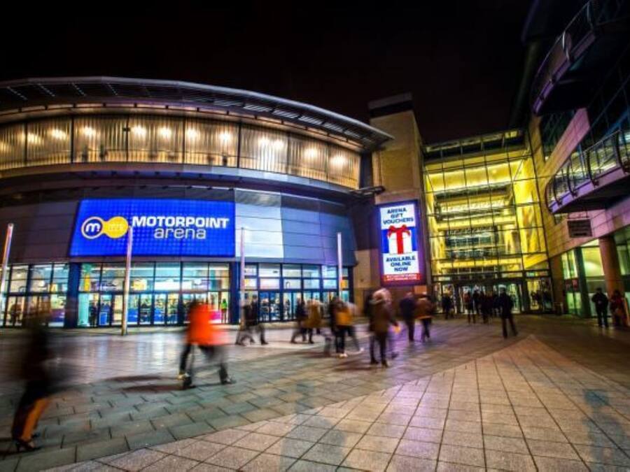 Um edifício moderno com fachada curva e uma placa azul destacada com a inscrição 'MOTORPOINT arena'.