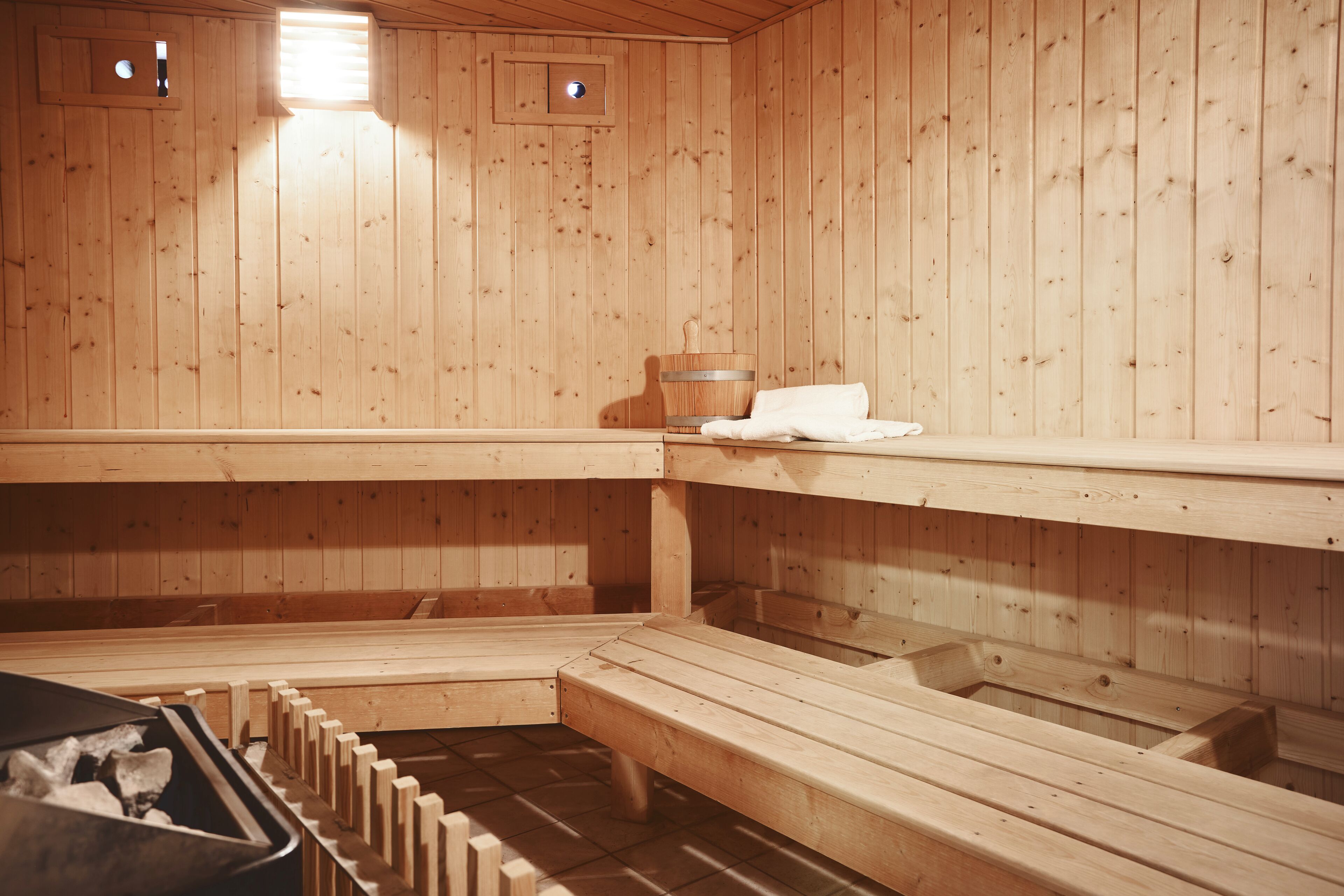 Uma sauna de madeira com bancos e um balde.