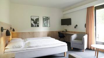 Quarto de hotel com uma cama, uma escrivaninha, uma cadeira e uma televisão.