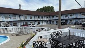 Um motel com área de estar externa, piscina e estacionamento.