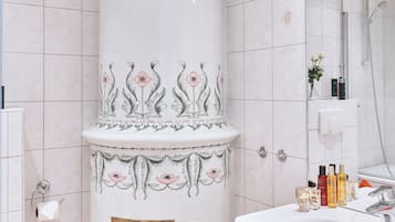 Casa de banho com um pilar branco decorativo, uma pia com produtos de higiene e uma área de duche.