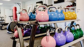 Diversos kettlebells coloridos em um espaço de academia.
