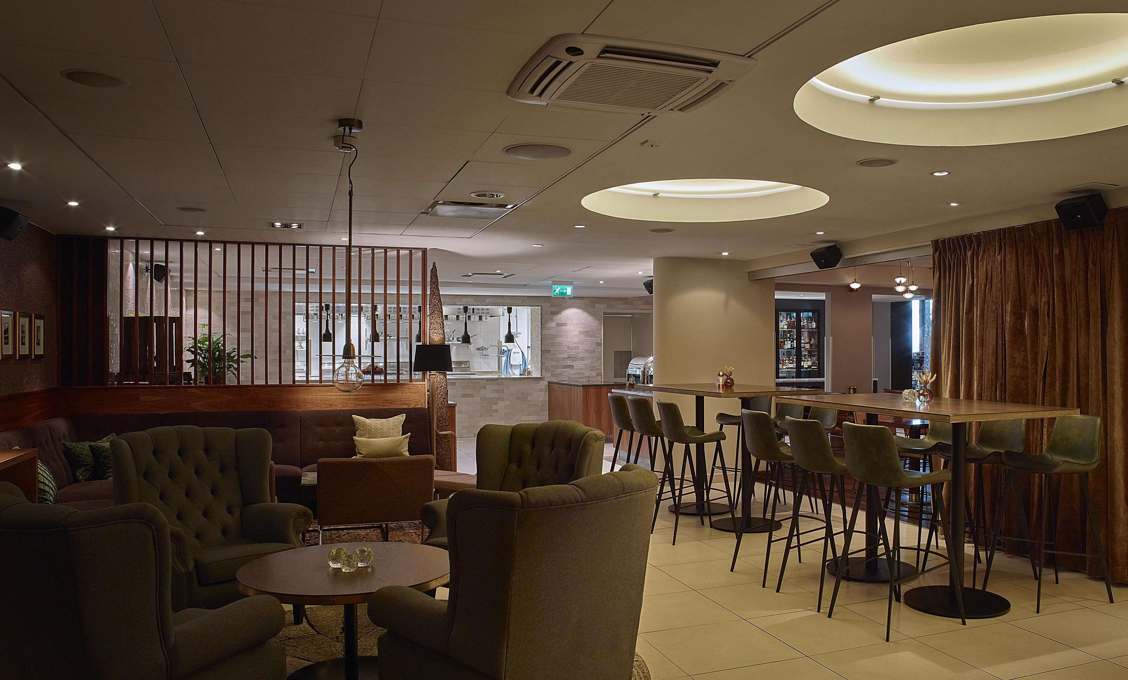 Um interior moderno com área de bar, assentos e cozinha ao fundo.