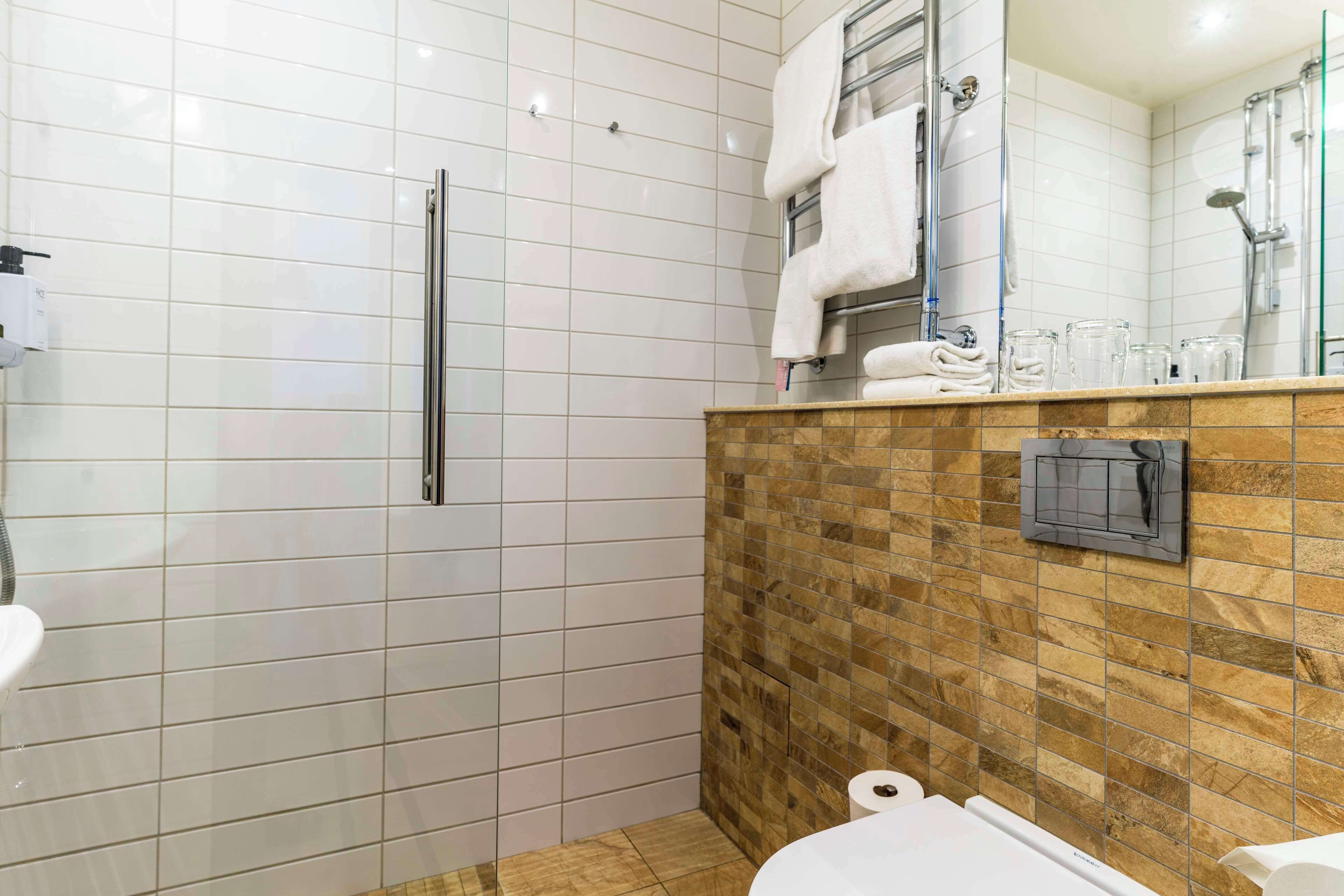 Uma casa de banho moderna com chuveiro, sanita e lavatório.