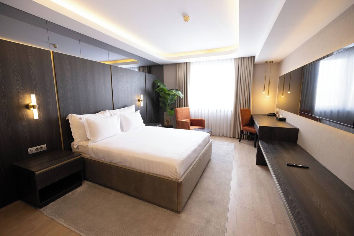 Quarto de hotel moderno com uma cama grande, uma mesa e um espaço de estar.