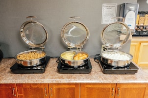 Disposição de buffet com três recipientes de comida sobre um balcão.
