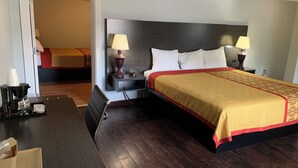 Quarto de hotel com uma cama grande, duas mesas de cabeceira com luminárias, uma escrivaninha com cafeteira e uma cadeira.