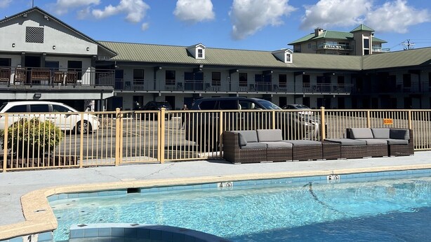 Um hotel com piscina, área de estar ao ar livre e estacionamento cercado.