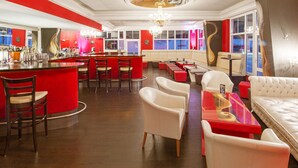 Um saguão de hotel moderno com área de bar, disposição de assentos e um lustre.