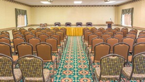 Uma sala de conferências com fileiras de cadeiras, um púlpito e um carpete estampado.