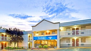 Um Travelodge com entrada para o saguão, uma varanda à direita e uma árvore na frente.