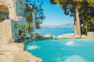 Piscina azul límpida rodeada por formações rochosas e árvores.