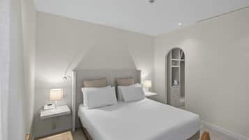 Quarto moderno com cama grande, luminárias de cabeceira, mesa de cabeceira e guarda-roupa embutido.