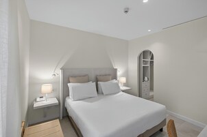 Quarto moderno com cama grande, luminárias de cabeceira, mesa de cabeceira e guarda-roupa embutido.