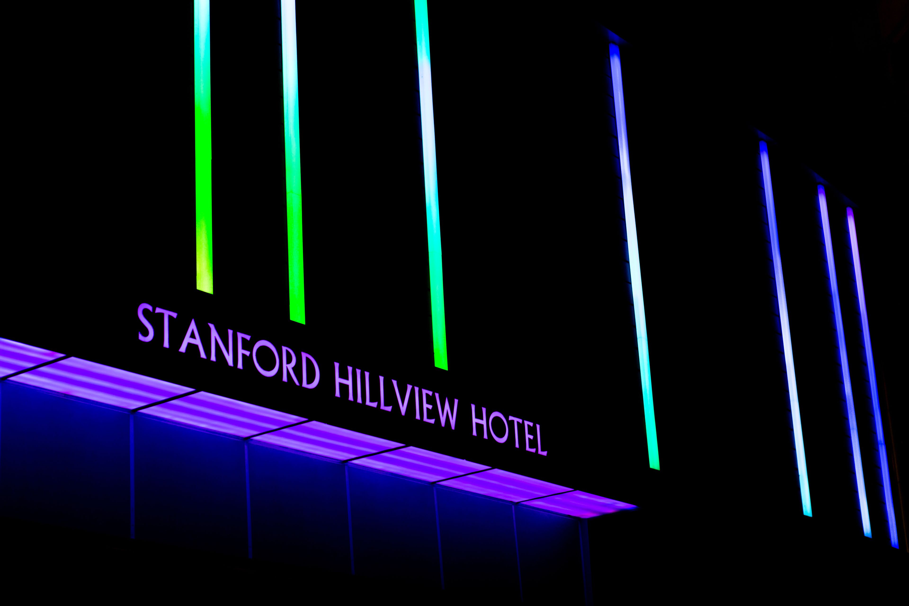 Placa do Hotel Stanford Hillview com luzes de neon verticais.