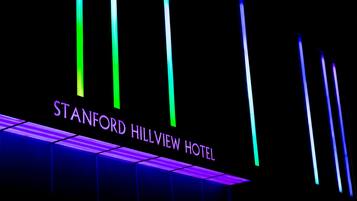 Placa do Hotel Stanford Hillview com luzes de neon verticais.
