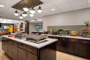 Cozinha moderna com ilha central, eletrodomésticos embutidos e diversos alimentos.