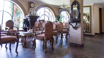 Um quarto espaçoso com mobiliário requintado, grandes janelas e um espelho imponente.
