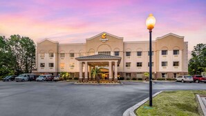 Um hotel Comfort Inn com entrada central, vários espaços de estacionamento e um gramado bem cuidado.