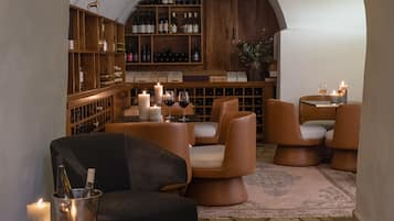 Uma área de estar acolhedora com poltronas de couro, um tapete estampado e um espaço para exibir vinhos.
