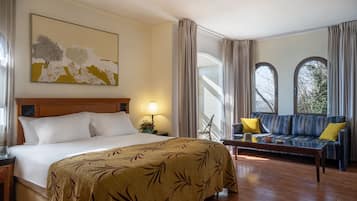 Quarto de hotel com uma cama grande, um sofá, uma mesa de centro e um quadro na parede.