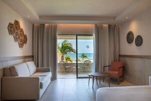 Quarto de hotel com varanda, sofá, poltrona e cama.