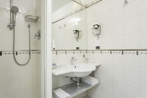 Casa de banho moderna com chuveiro, pia e porta-toalhas.