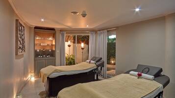 Sala de spa com duas mesas de massagem, uma receção e vista para o exterior.