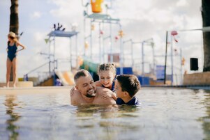 Área de piscina com um escorrega aquático e uma torre de salva-vidas ao fundo.