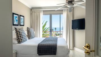 Quarto de hotel com cama, televisão e vista para o mar.