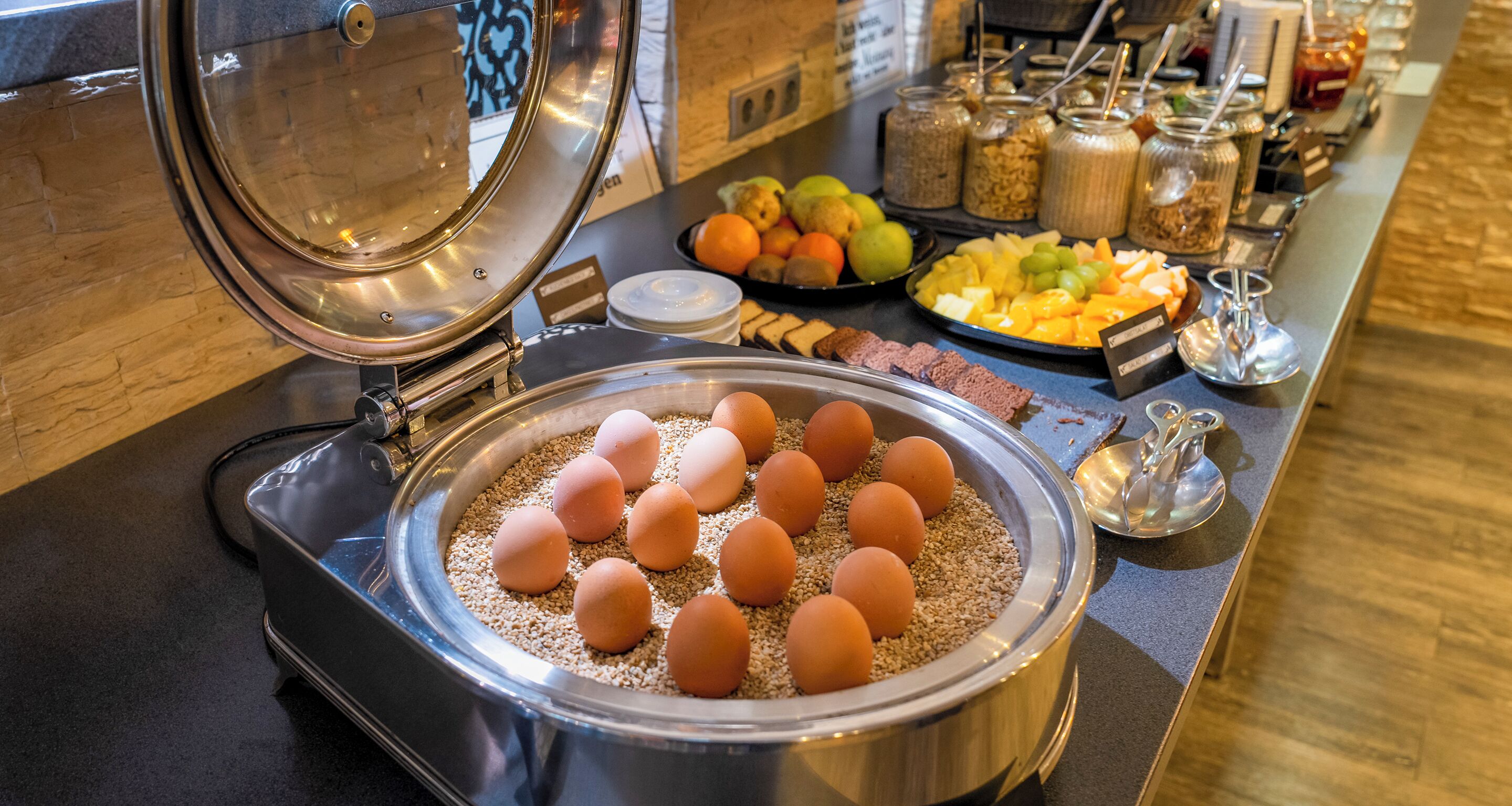 Buffet com diversos alimentos, incluindo ovos, frutas e cereais.