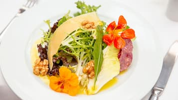 Um prato branco com salada, nozes e flores.