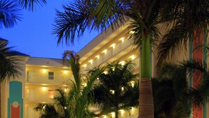Um saguão de hotel com área de piscina, com assentos ao ar livre e palmeiras.