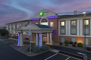 Um hotel Holiday Inn Express com fachada de tijolos, entrada coberta e estacionamento.