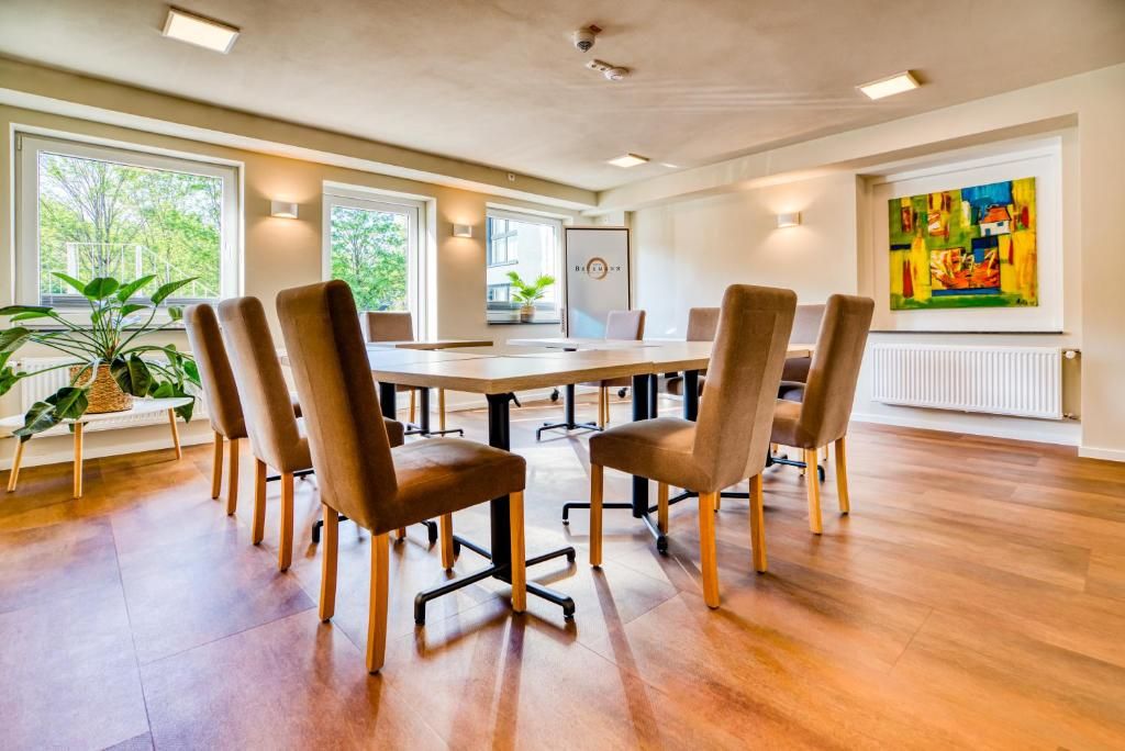 Uma sala de conferência com uma mesa comprida e seis cadeiras, janelas amplas e um quadro na parede.