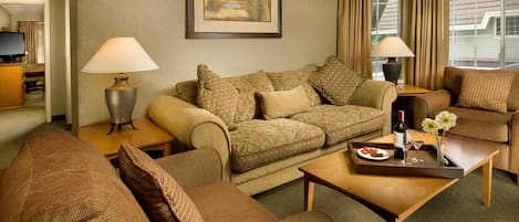Quarto de hotel com sofá, duas luminárias, um quadro na parede e uma mesinha com bandeja.