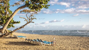 Na praia, praia de areia branca, espreguiçadeiras, guarda-sóis de praia 
