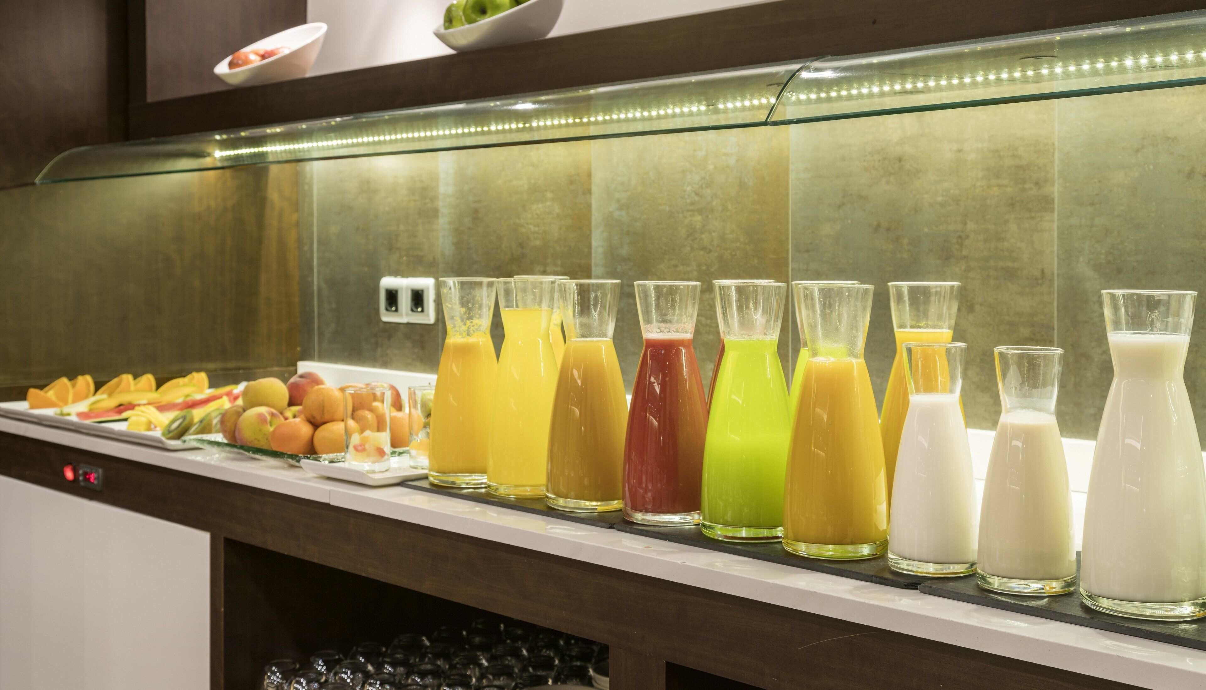 Um balcão de buffet com diversos sucos e frutas.