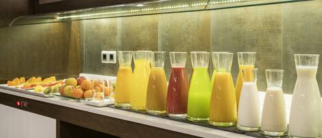 Um balcão de buffet com diversos sucos e frutas.