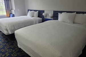 Quarto de hotel com duas camas, carpete estampado e janela com cortinas.