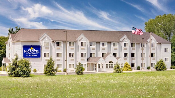 Um Microtel Inn & Suites by Wyndham com uma grande placa, várias janelas e uma bandeira.