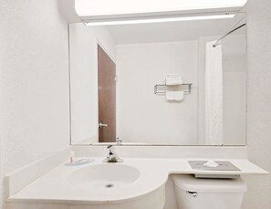 Um banheiro moderno com pia branca, espelho, vaso sanitário e chuveiro.
